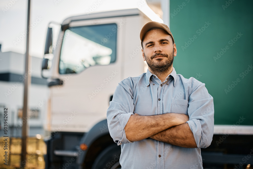 Truck driver standing with arms crossed in front of his truck and ...