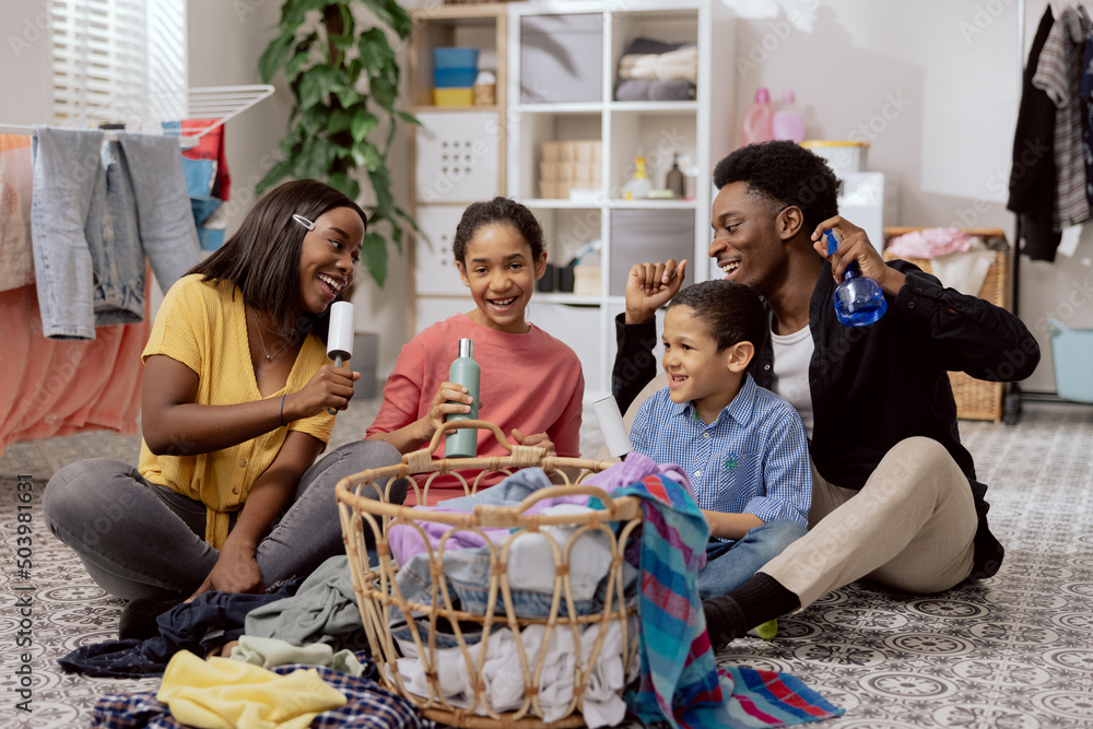 A family sits on the laundry room floor sorting clothes before putting ...