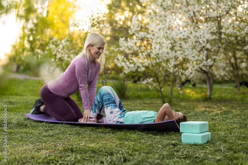 Young sports mother doing physics exercise outdoors in garden near her ...