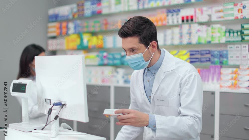 Male pharmacist in medical mask and white uniform holding pills and ...