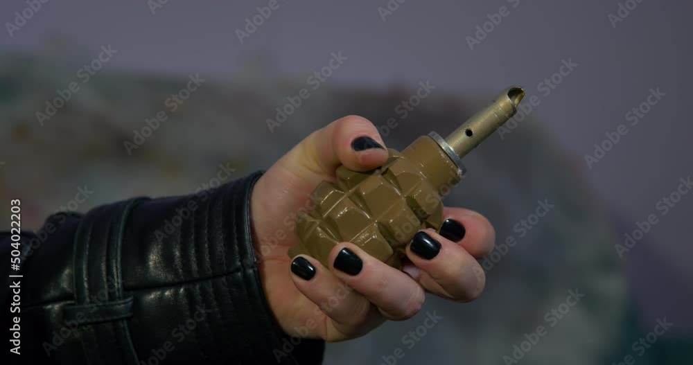Criminal woman in leather jacket activates hand grenade on blurred ...