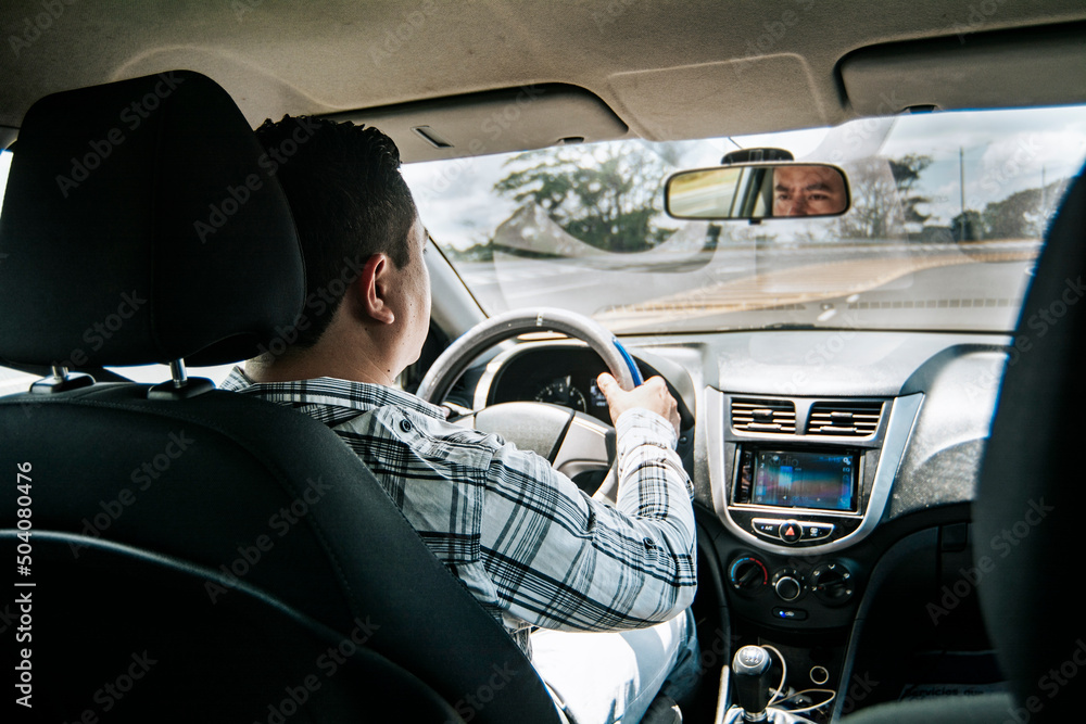 Back view of a man driving a car, Man's hands on the wheel of the car ...