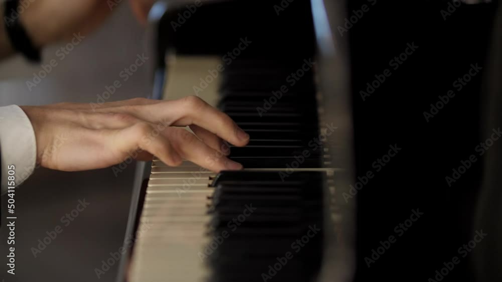 Male hands playing grand piano in a busy place with people walking ...