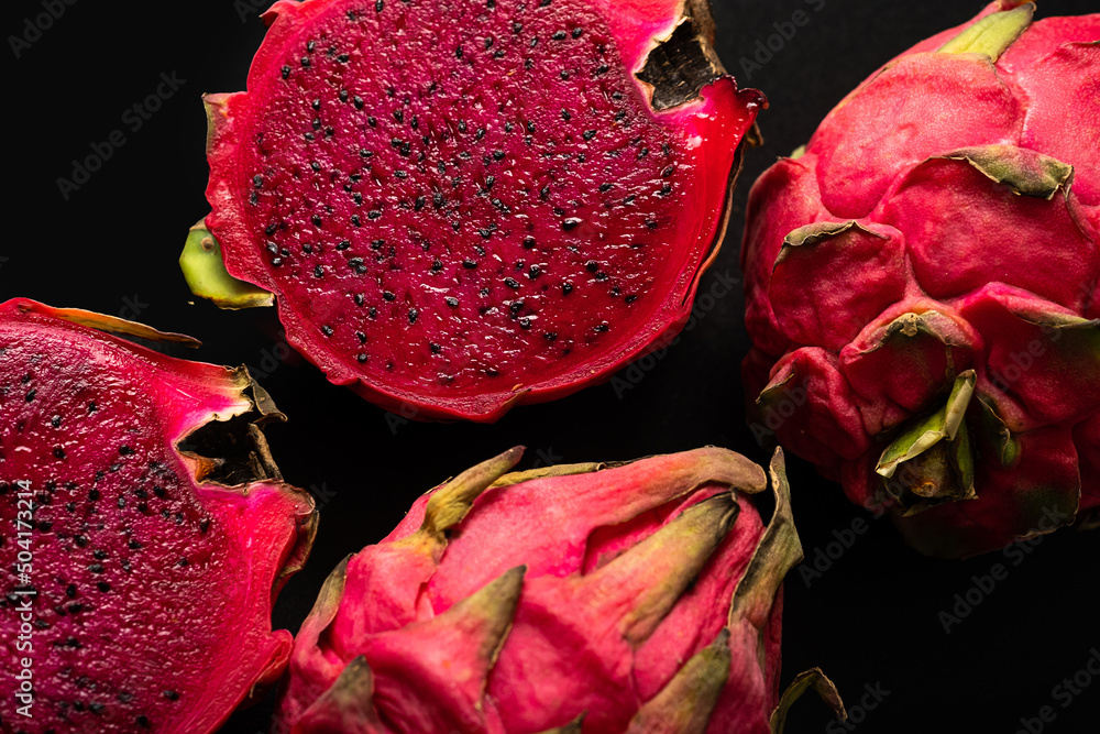 Juicy ripe pitahaya whole and scattered on a black background. View ...
