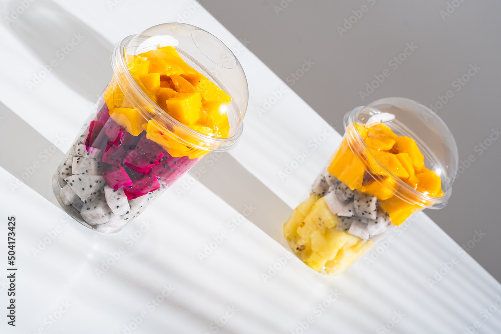 Sliced exotic Thai fruits in a plastic cup, snacks to take away. Mango ...