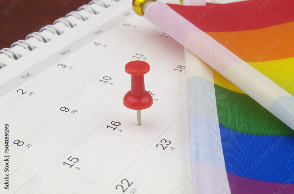 LGBT event concept. One push pin on calendar page and LGBT pride flags ...