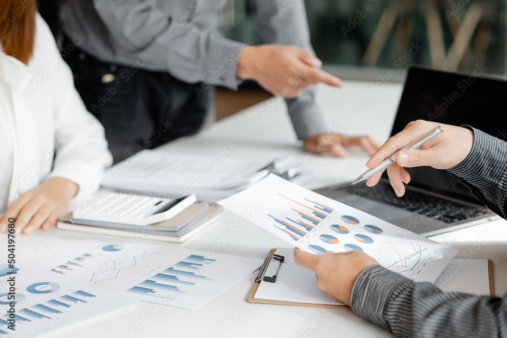 A desk in a company conference room has a group of business people ...