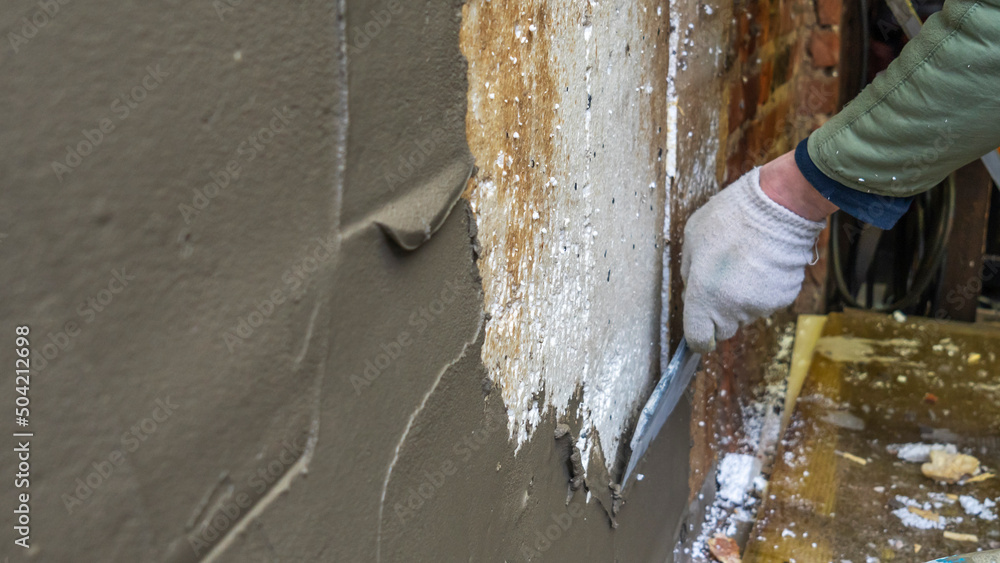 A plasterer applies plaster with a spatula to a brick wall. Wall ...