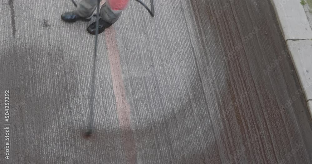 Road worker spraying bitumen emulsion with the hand spray lance before ...