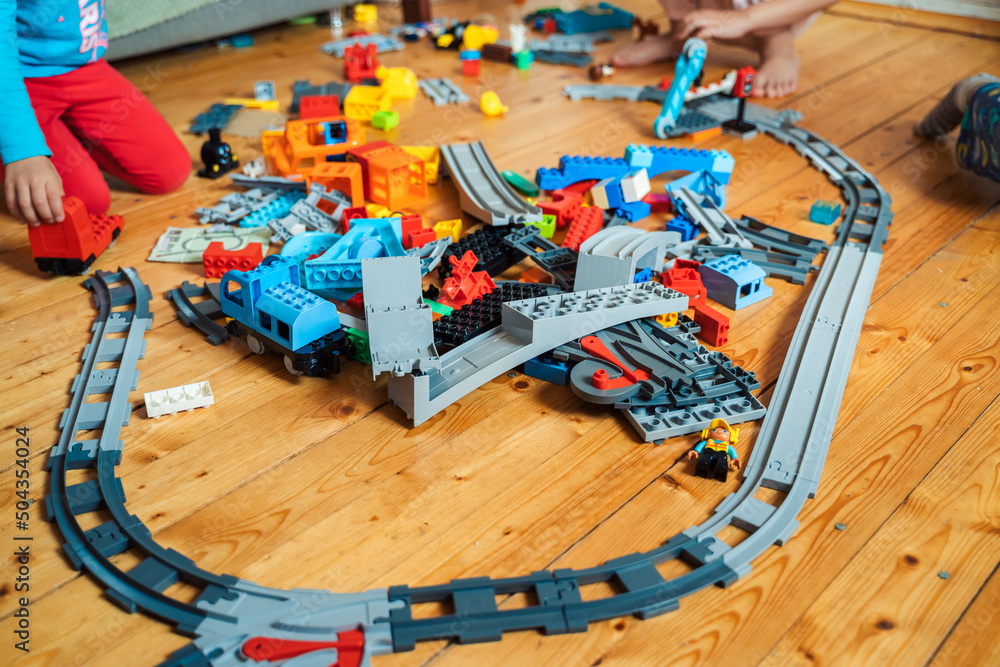 Girls, sisters play kids constructor, build toy railway, railroad by ...