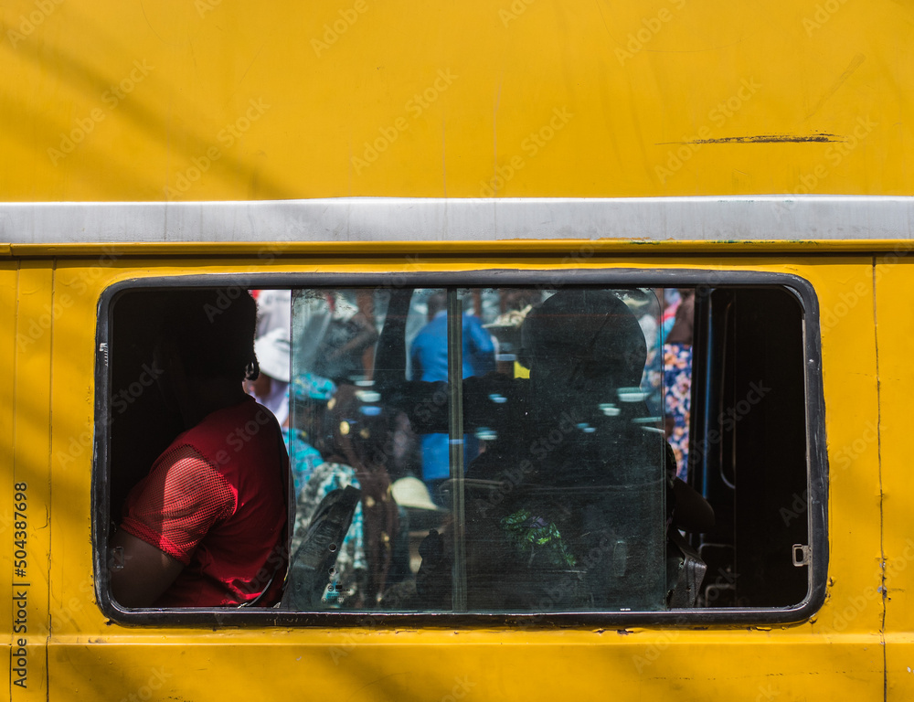 A passenger is seen in a yellow danfo bus through the window in Lagos ...