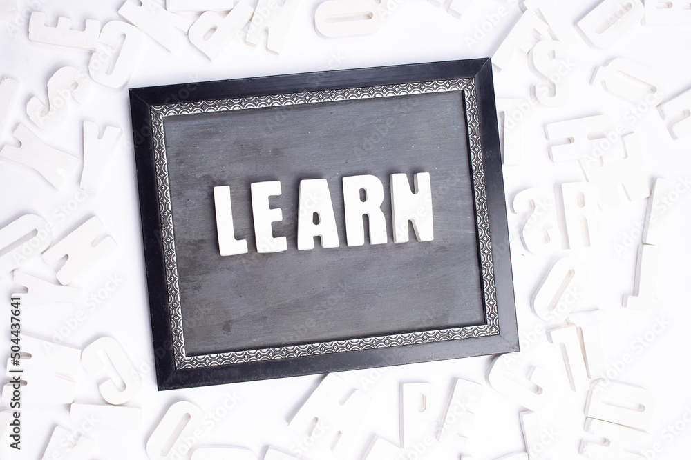 Loose white letters on black board forming the word learn. Education ...