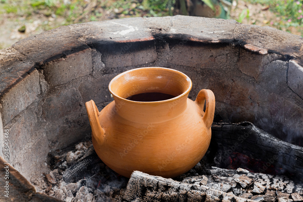 Clay pot on a traditional stove with burned wood and ashes Stock Photo ...