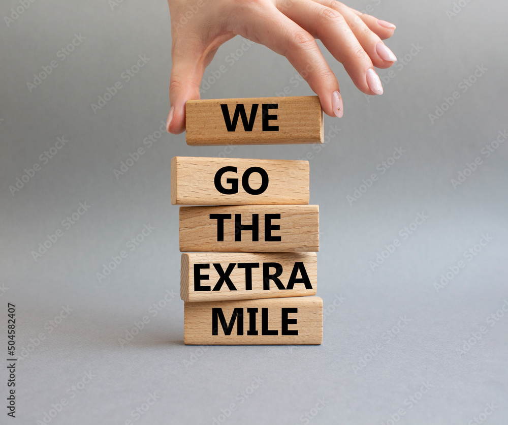 We go the extra mile symbol. Wooden blocks with words 'We go the extra ...