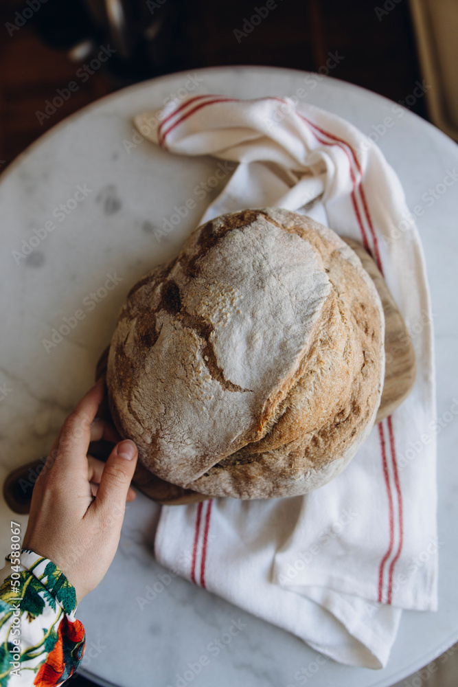 whole round bread cooked on sourdough lies on the kitchen table top ...