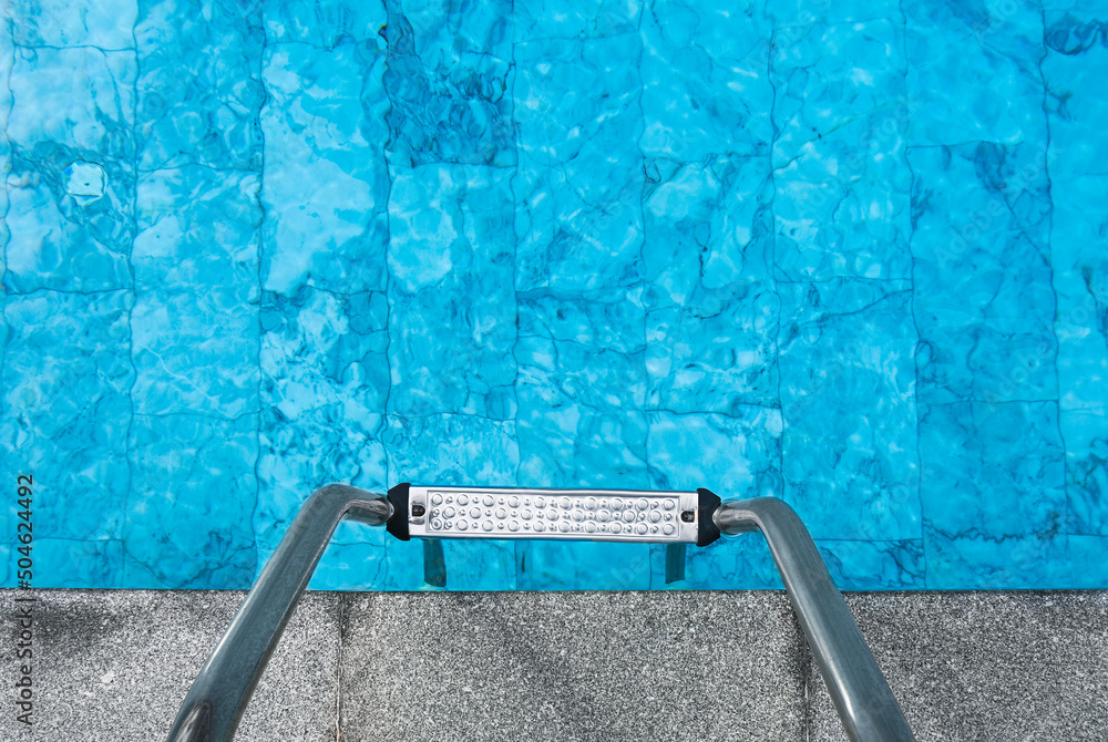 Ladder on the poolside top view. Sunshine through the clear water of ...