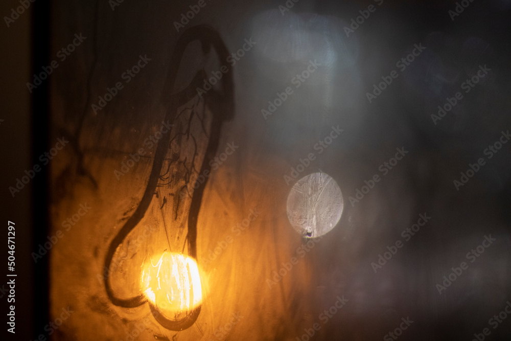 Drawing on wet glass. Foggy window. Warm light is reflected in surface ...