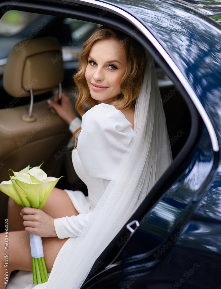 Beautiful caucasian blonde bride sitting in a stylish car with a ...