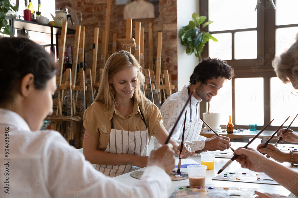 In workshop group of diverse people sit at table attend art therapy ...