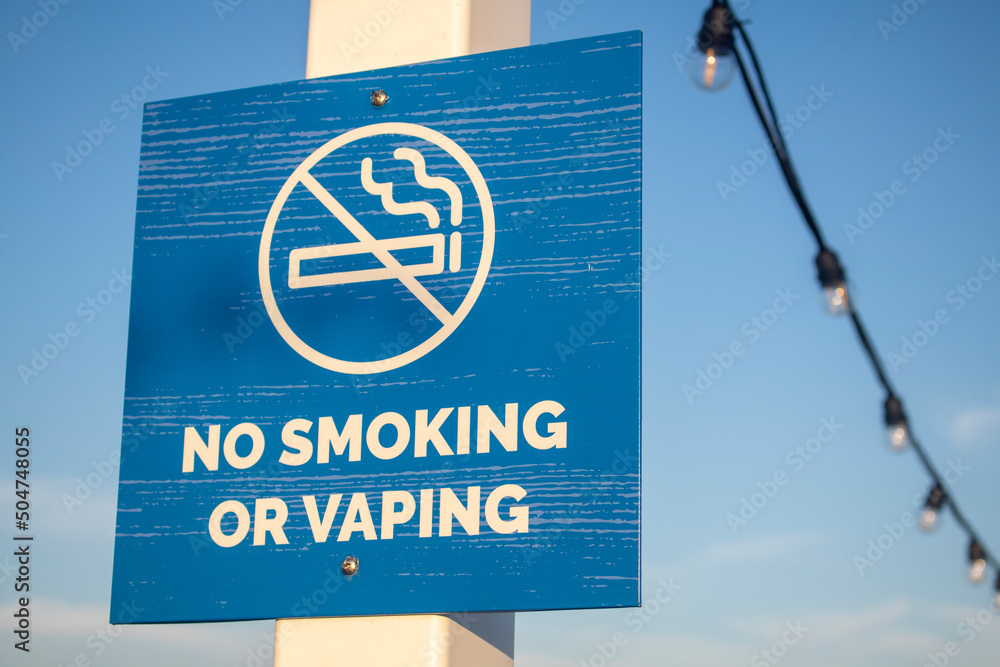 blue and white square sign with smoking icon slash and text reading No ...