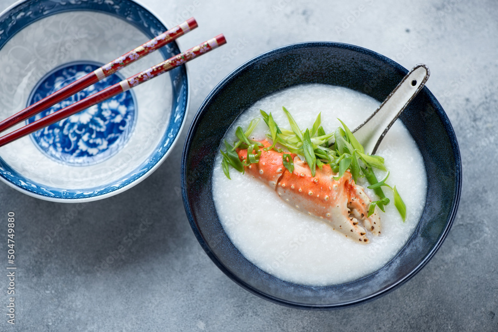 Dark-blue bowl of asian congee with crab and scallions, high angle view ...