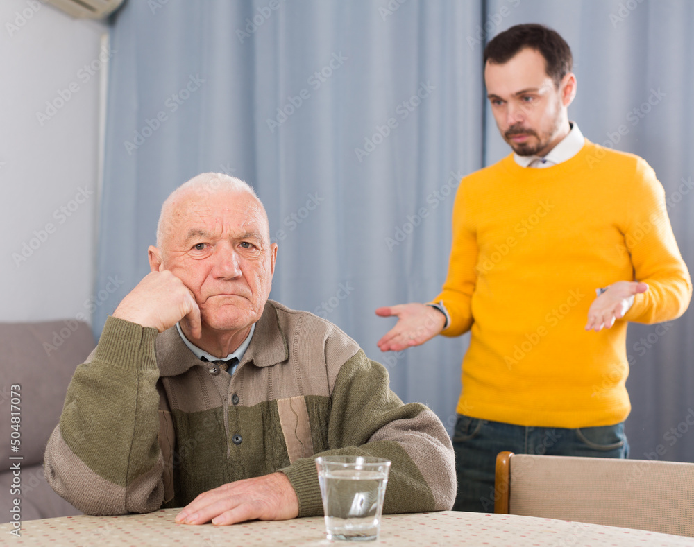 Elderly father and his son are serious conversation at home and solve ...