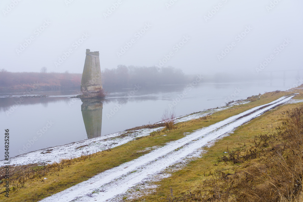 Concrete support of the blown up bridge on the river in damp foggy ...