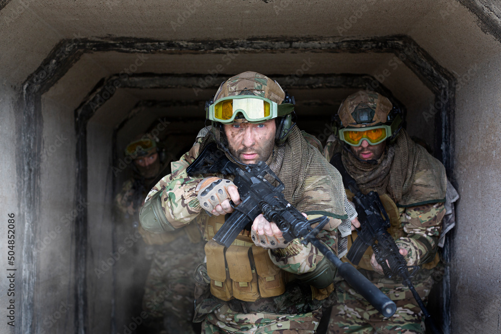Three military mercenaries walk against the background of a concrete ...