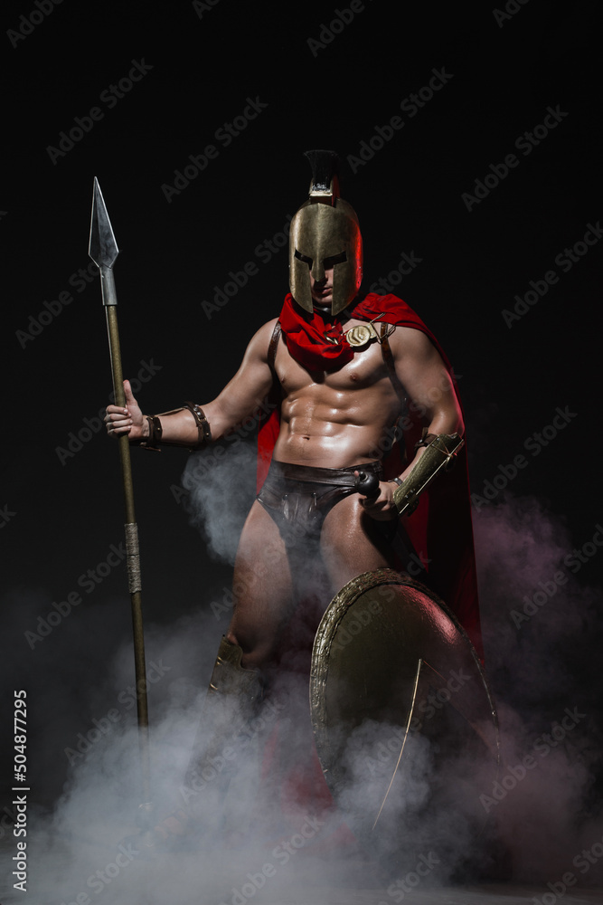 A young athletic man dressed as a Roman soldier in a red cloak stands ...
