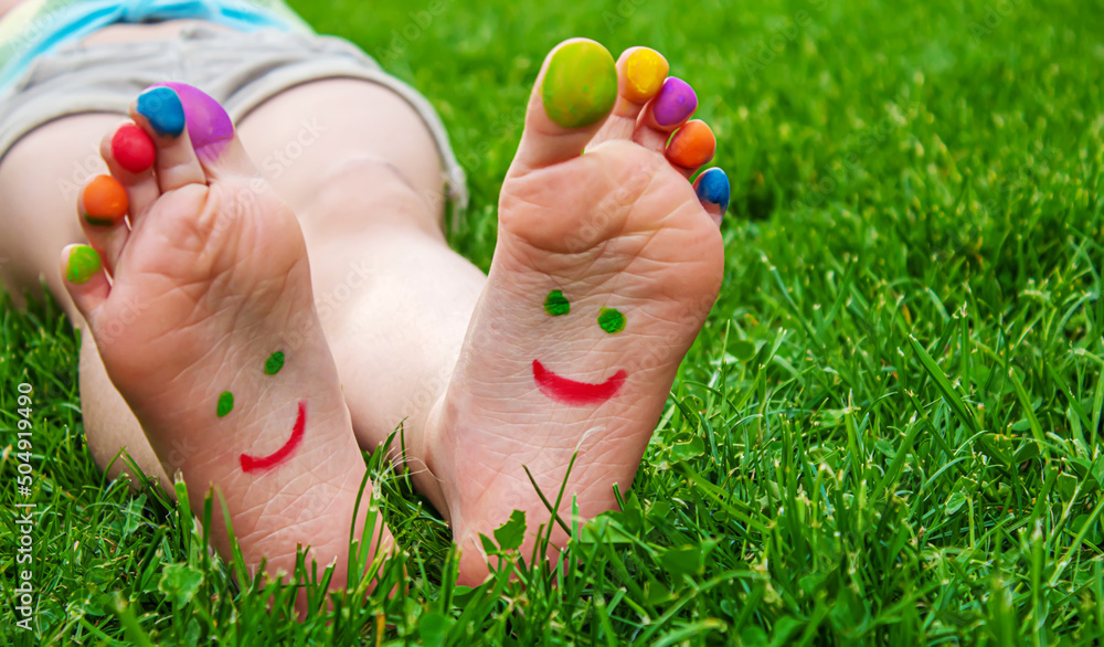 Children's feet with a pattern of paints smile on the green grass ...