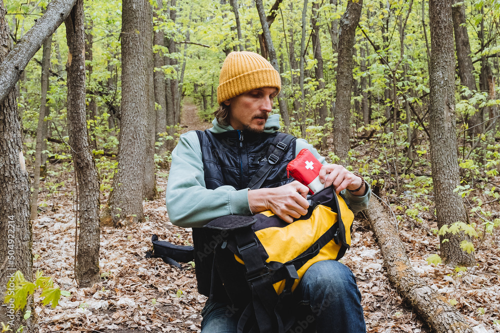 Put a first aid kit with medicines in a backpack, a guy a tourist in ...