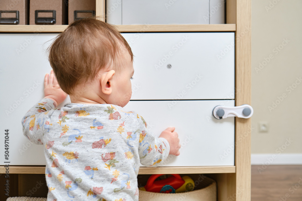 Toddler baby boy rips off a cabinet drawer with his hand. The child ...