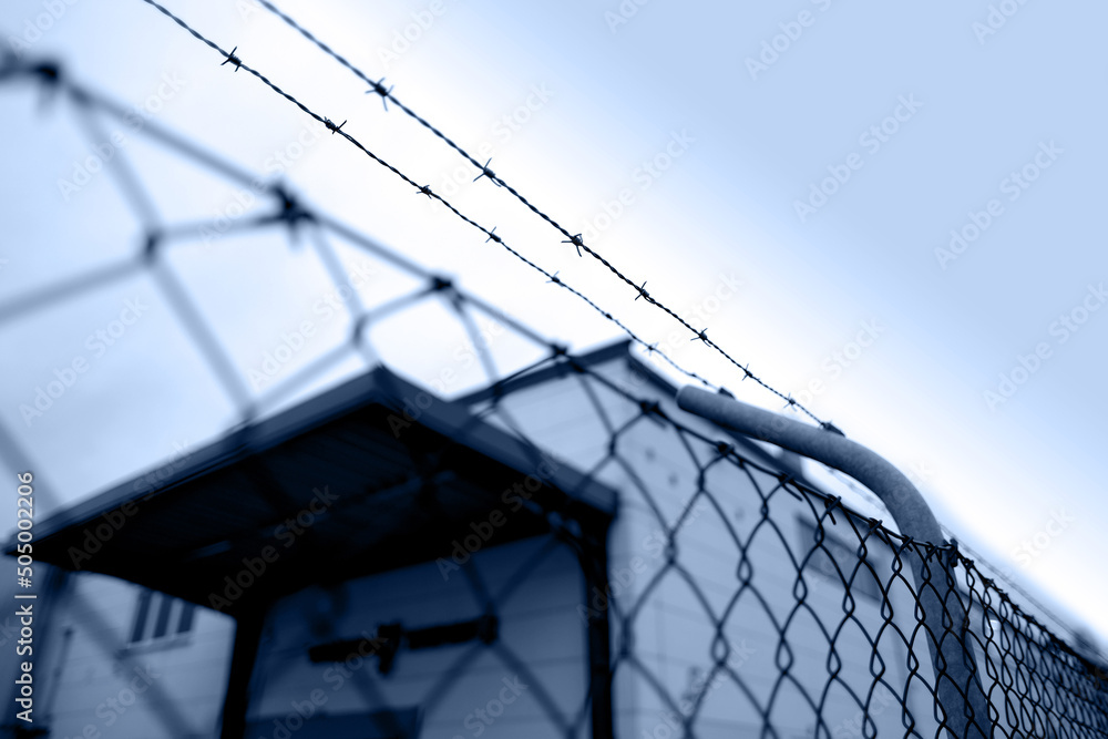 many rows of barbedwire, wire mesh, barbed wire fence on top, building ...