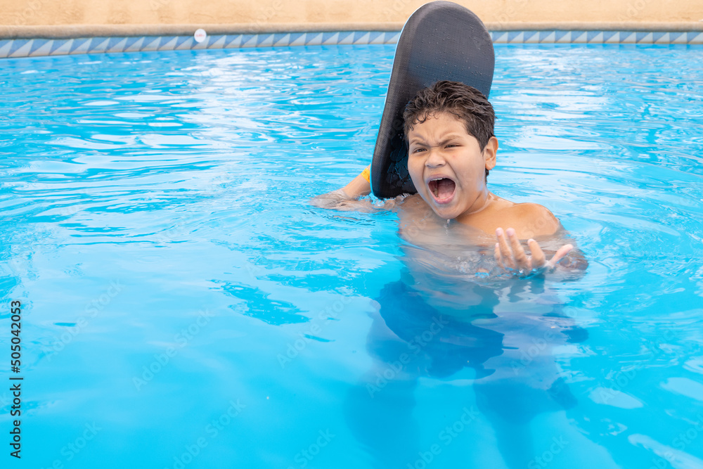 boy screaming in the pool with a board on his head, summer vacation is ...