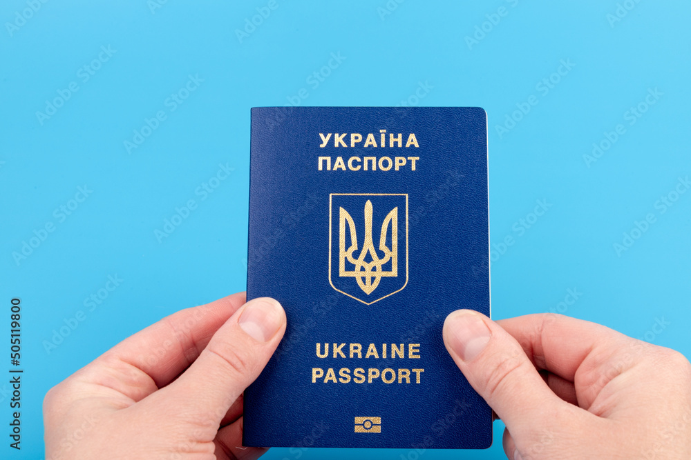 Passport of a citizen of Ukraine in a female hand on a blue background ...