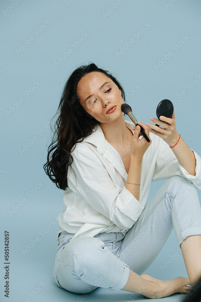 Beautiful vitiligo brunette sitting on the floor, powdering her face ...