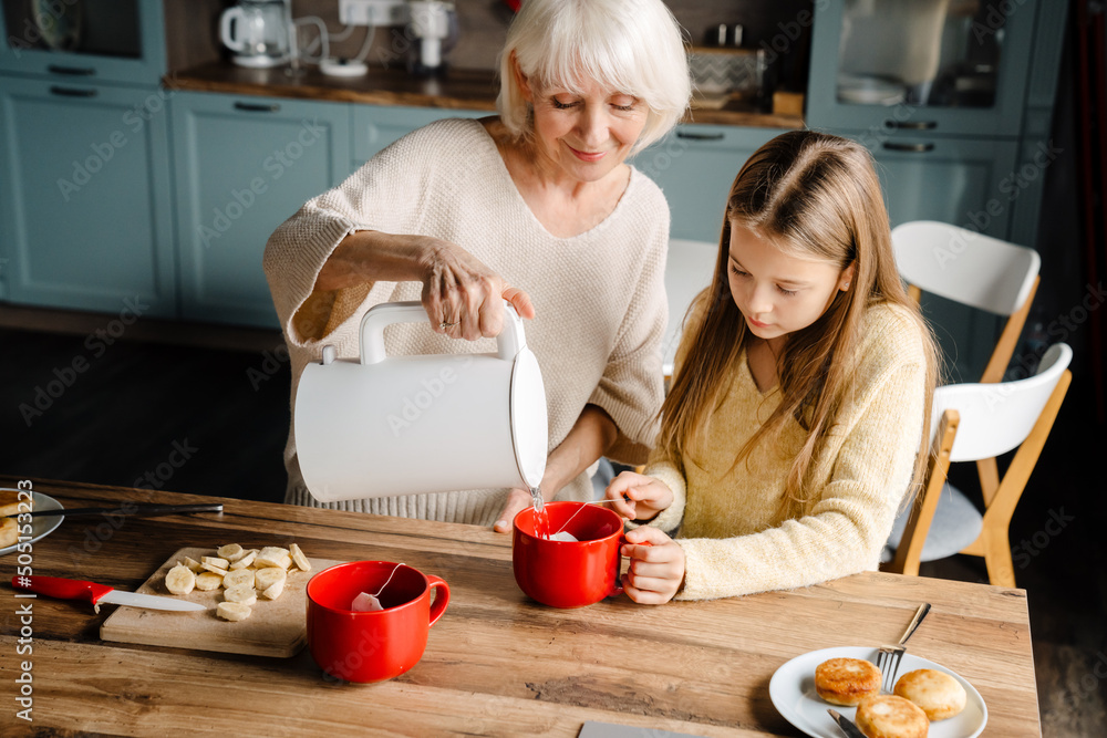 Happy grandmother and granddaughter cooking breakfast together Stock ...