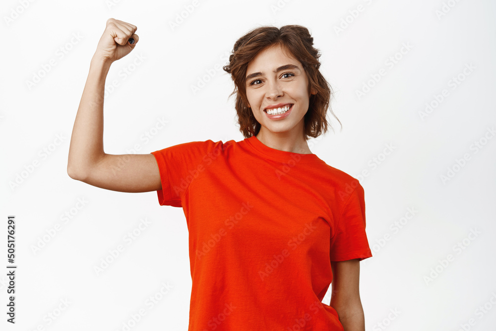 Workout and strong woman concept. Smiling young woman showing biceps ...