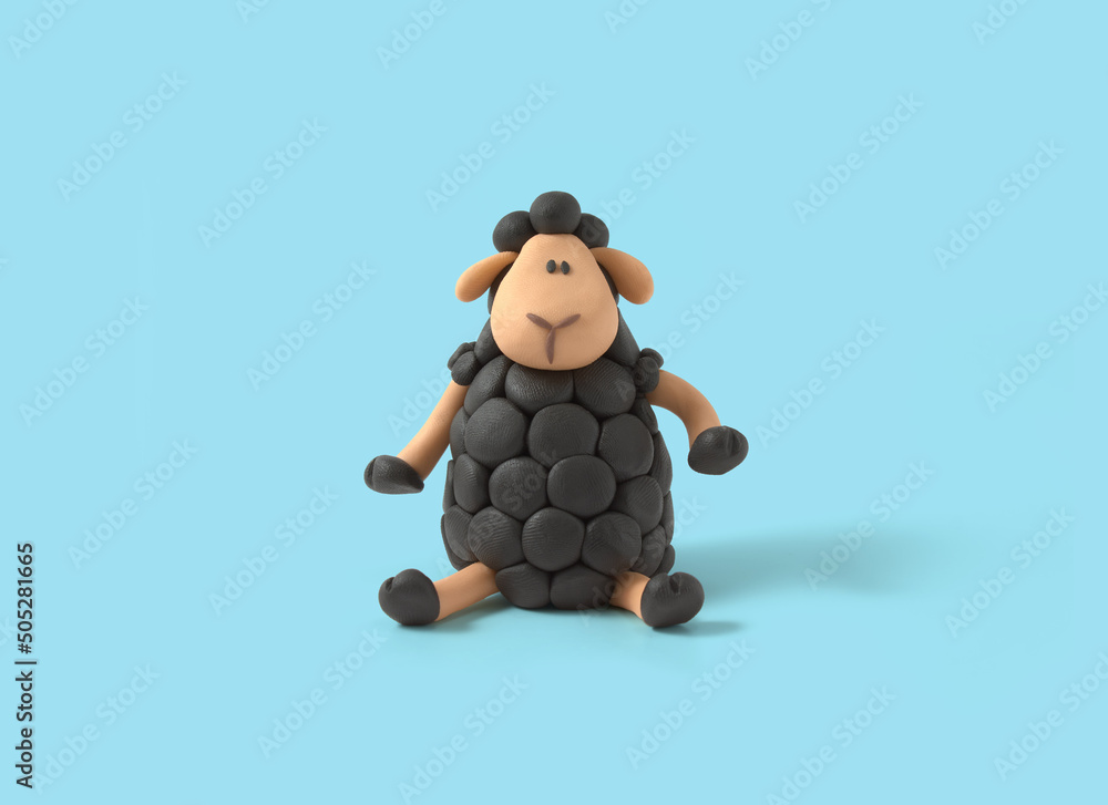 Cute sitting black sheep made of plasticine on blue background, Clay ...