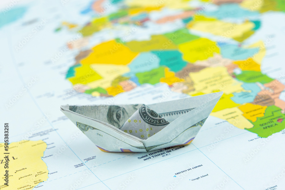 Paper ship made of dollars on world map, ship transportation concept ...