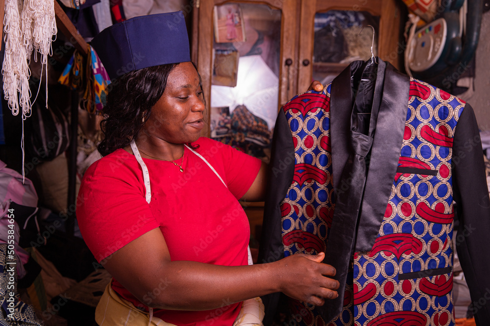 African woman seamstress in her tailoring workshop in the middle of her ...