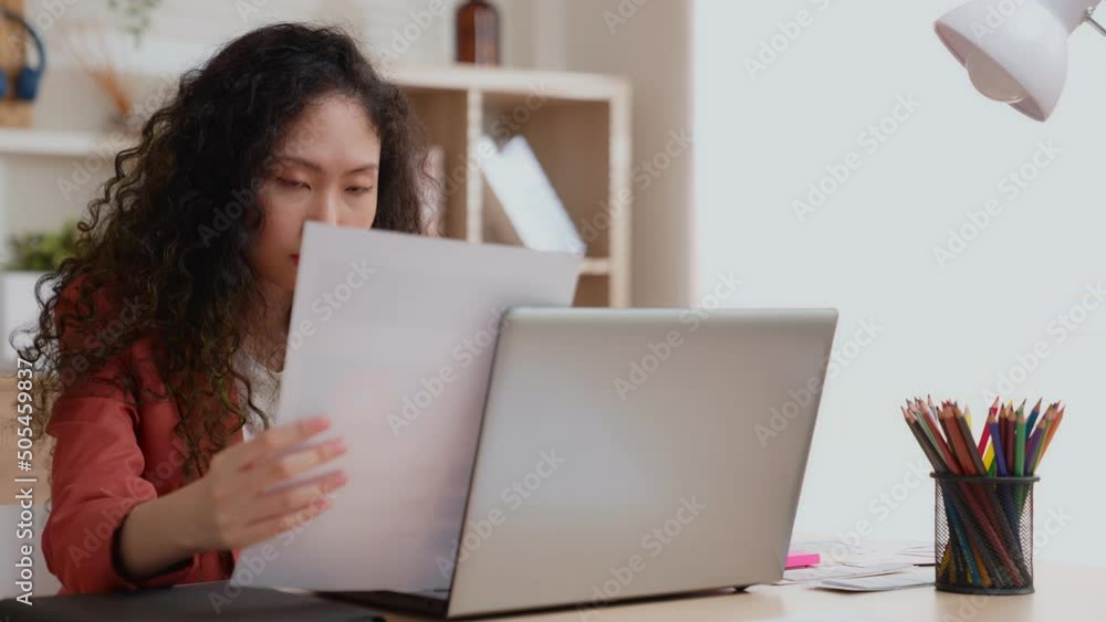 Asian designer woman compare paper work sheet before submitting to ...