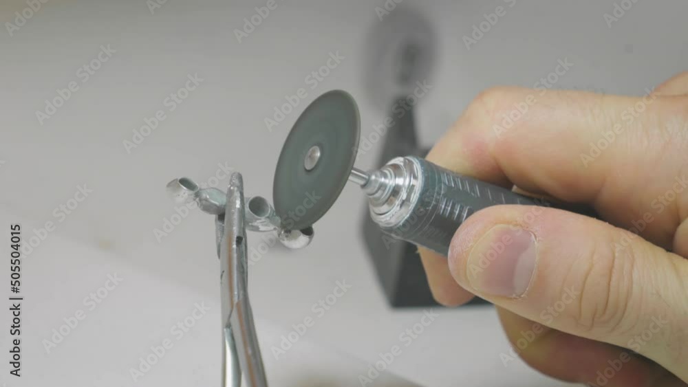 Using a cutting tool to make incisions in steel teeth bridge. Tool is ...