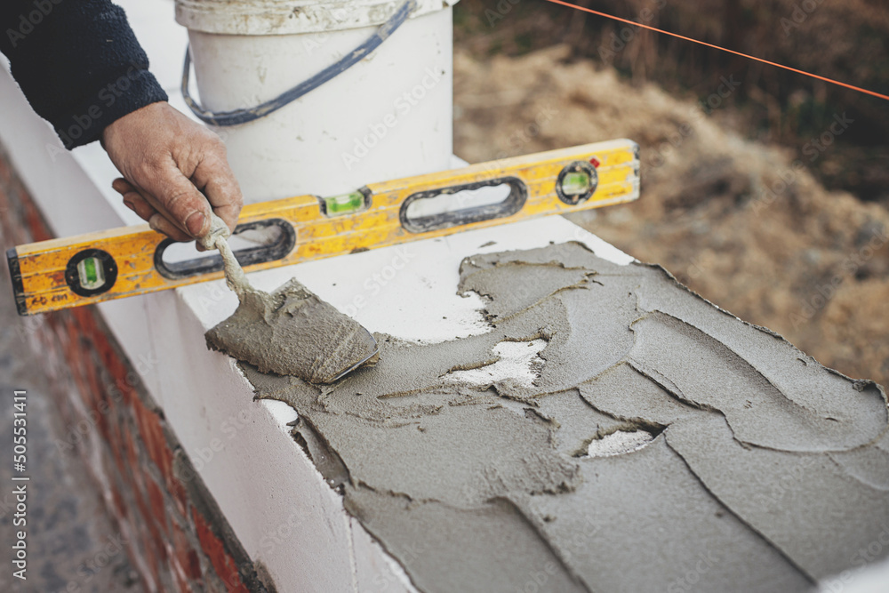 Worker laying autoclaved aerated concrete blocks, working with adhesive ...