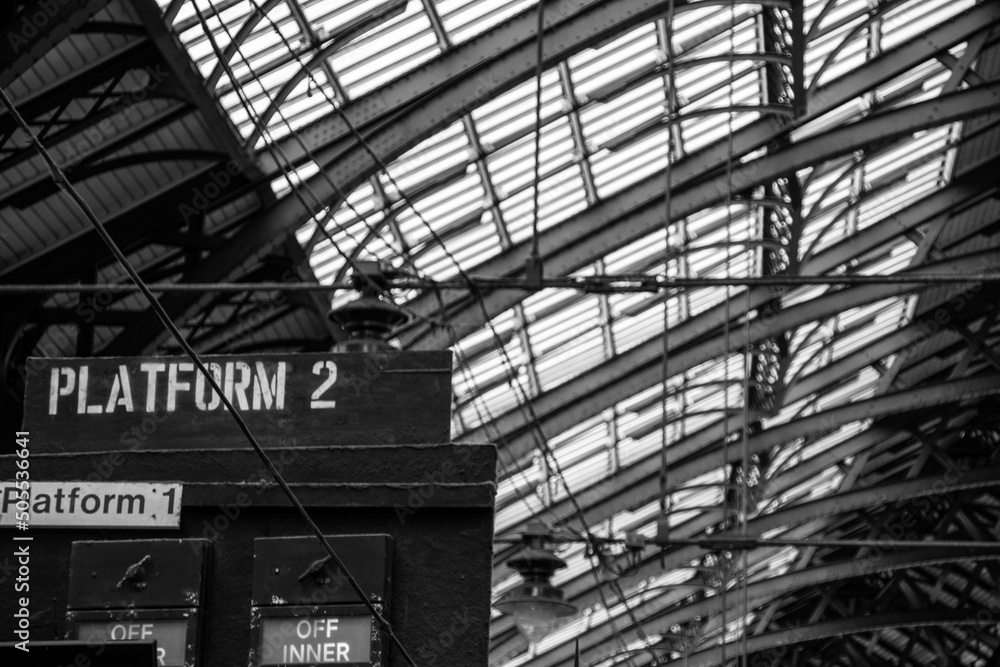 A railway station with a steel curved roof overhead and a sign ...