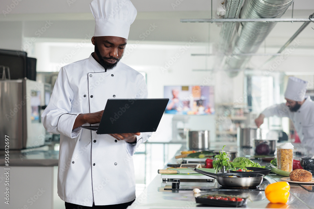 Food industry worker wearing cooking uniform using computer to inspire ...