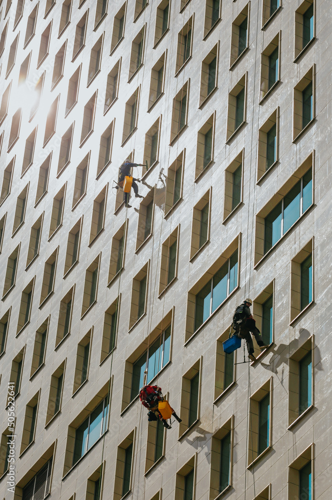 Industrial climbers wash windows of high-rise buildings. A group of ...