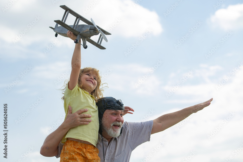 Young grandson and old grandfather having fun with plane outdoor on sky ...