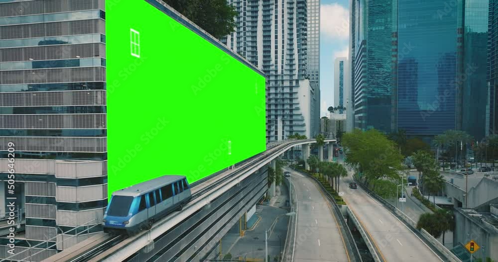 Urban train passing a green screen placeholder wall in a modern city ...