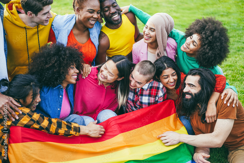 Diverse people having fun holding LGBT rainbow flag outdoor - Focus on ...